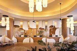 Um lobby de hotel moderno com balcão de recepção, área de estar e luminárias exclusivas.