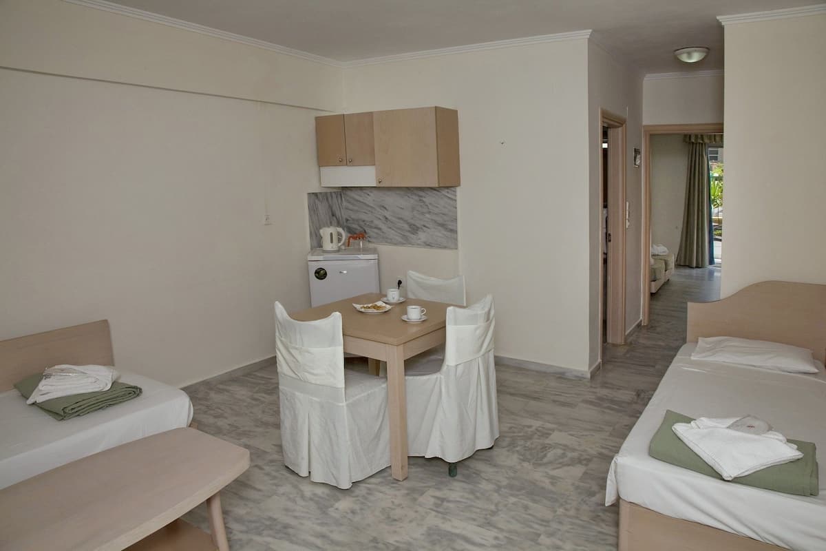 Quarto de hotel pequeno, com uma cama, uma escrivaninha com cadeira, cozinha compacta e vista para o exterior.