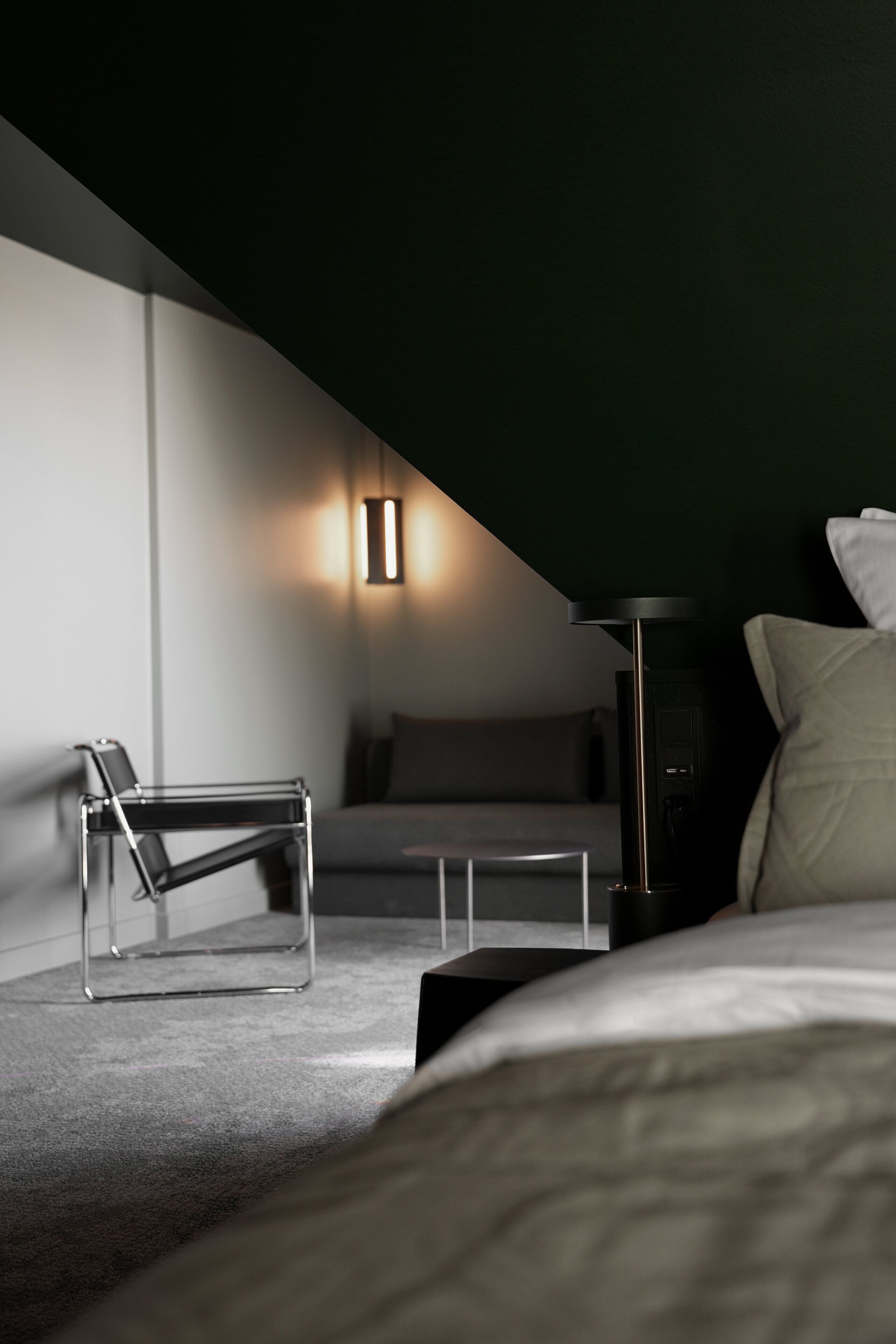 Quarto moderno com cama, poltrona, mesa de cabeceira e abajur.