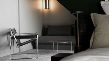 Quarto moderno com cama, poltrona, mesa de cabeceira e abajur.