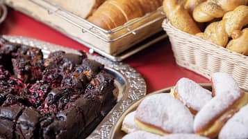 Diversos produtos de panificação, incluindo pão, doces e um bolo de chocolate.