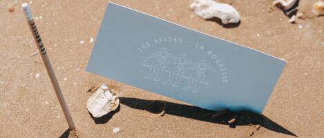 Um sinal de praia com o texto 'LES BAISES - LA ROCHELLE' e o contorno de pessoas.