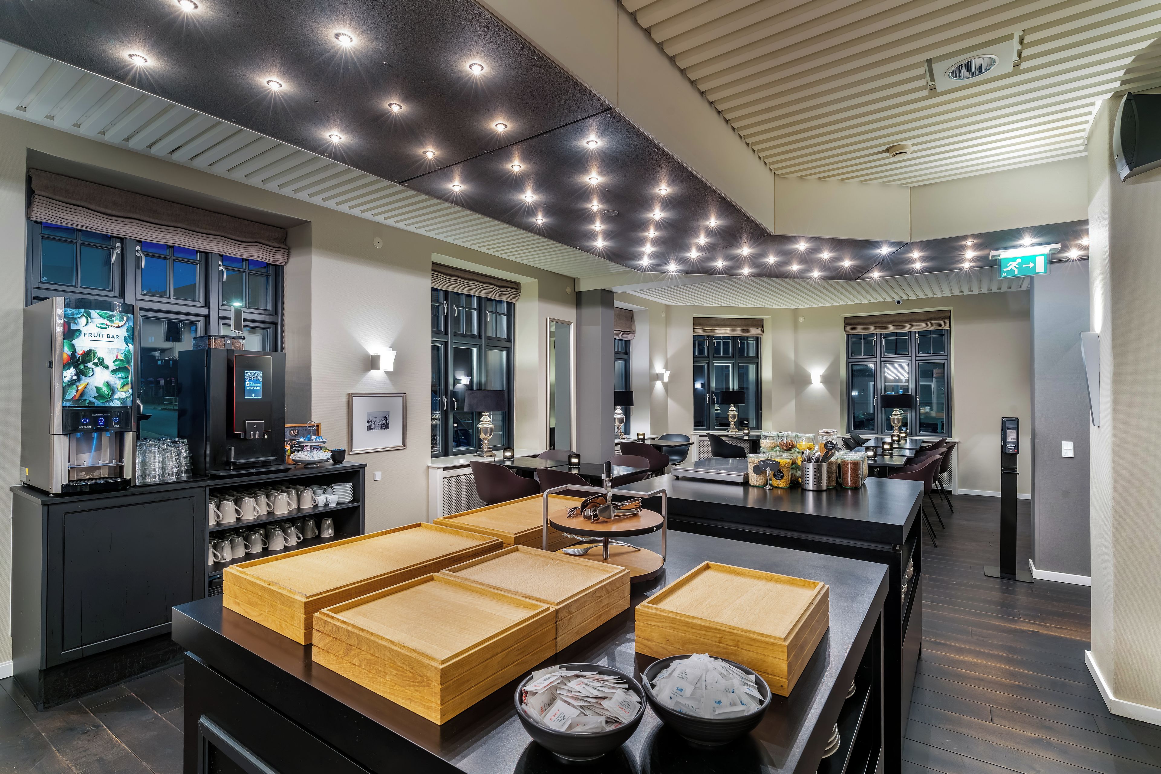 Um lobby moderno de hotel com um balcão de café, área de estar e uma receção.