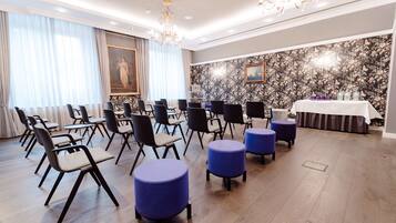 Uma sala de conferências com uma mesa comprida, cadeiras e pufes redondos.