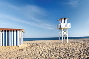 Uma praia com uma torre de salva-vidas e um prédio listrado.