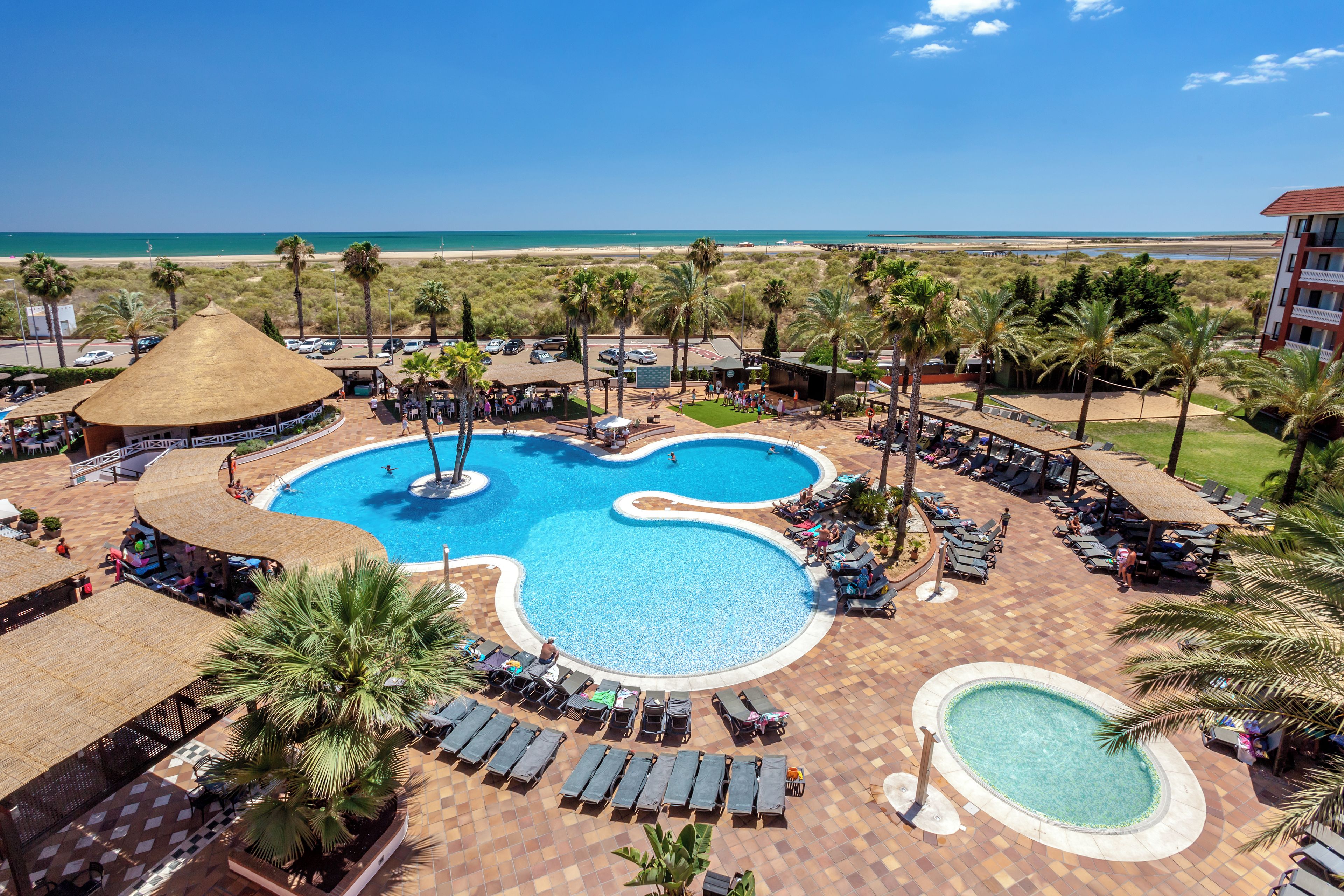 Resort com piscina principal ampla, várias piscinas menores e vista para a praia.
