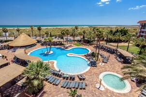 Resort com piscina principal ampla, várias piscinas menores e vista para a praia.