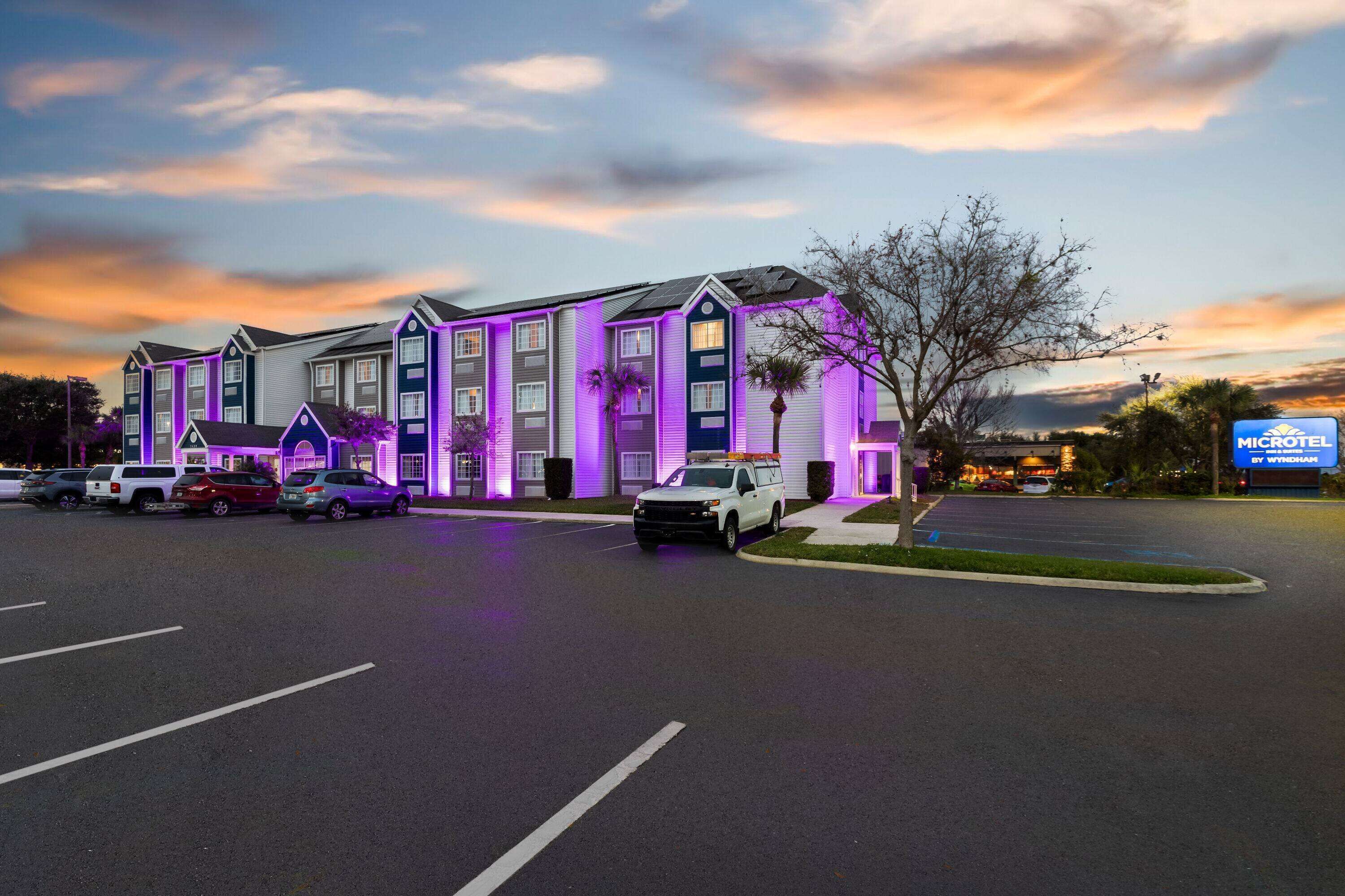 Um hotel com design moderno, apresentando um estacionamento e uma caminhonete branca estacionada na frente.