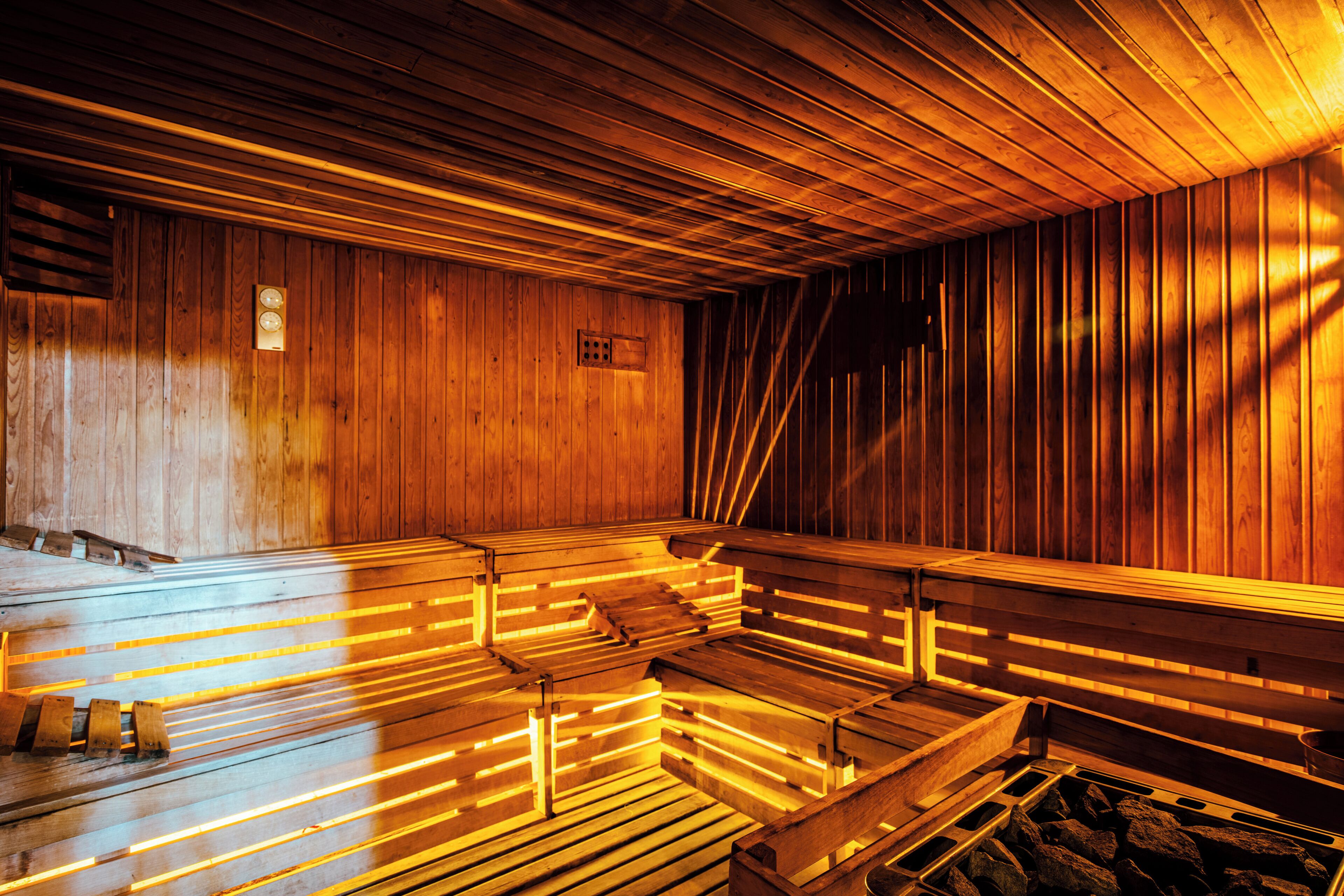 Uma sauna com bancos e assentos de madeira, paredes e chão de madeira.