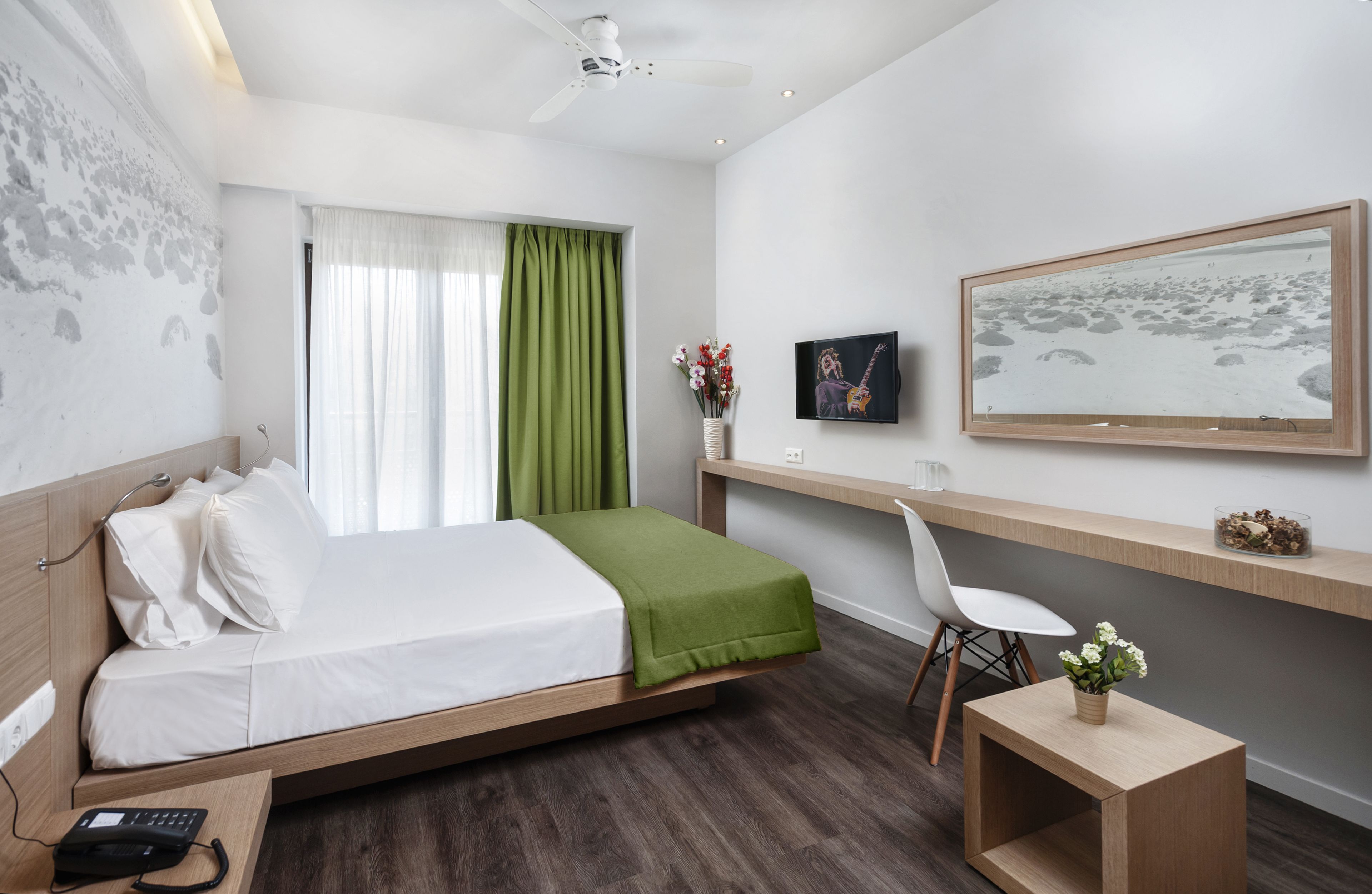 Quarto de hotel moderno com cama, escrivaninha, cadeira e obra de arte na parede.