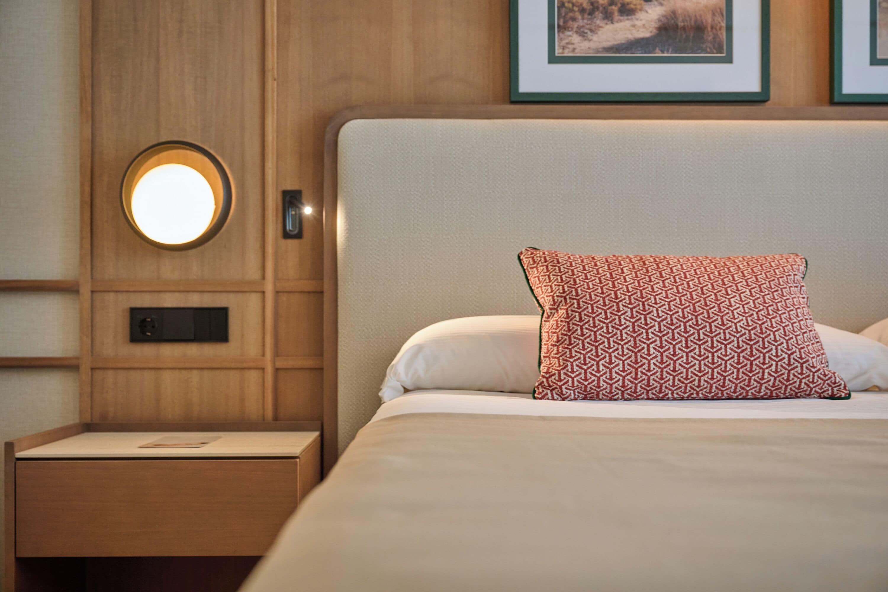 Quarto de hotel bem arrumado com uma cama, mesa de cabeceira e luminária na parede.
