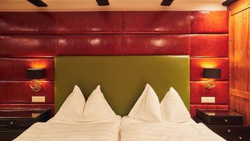 Quarto de hotel com uma cama grande, cabeceira verde e duas luminárias de cabeceira.