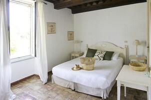 Quarto bem arrumado com uma cama grande, duas mesas de cabeceira e uma janela com cortinas.