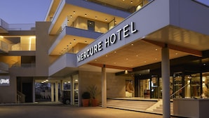 Um hotel moderno com uma placa de destaque, várias varandas e uma área de entrada coberta.