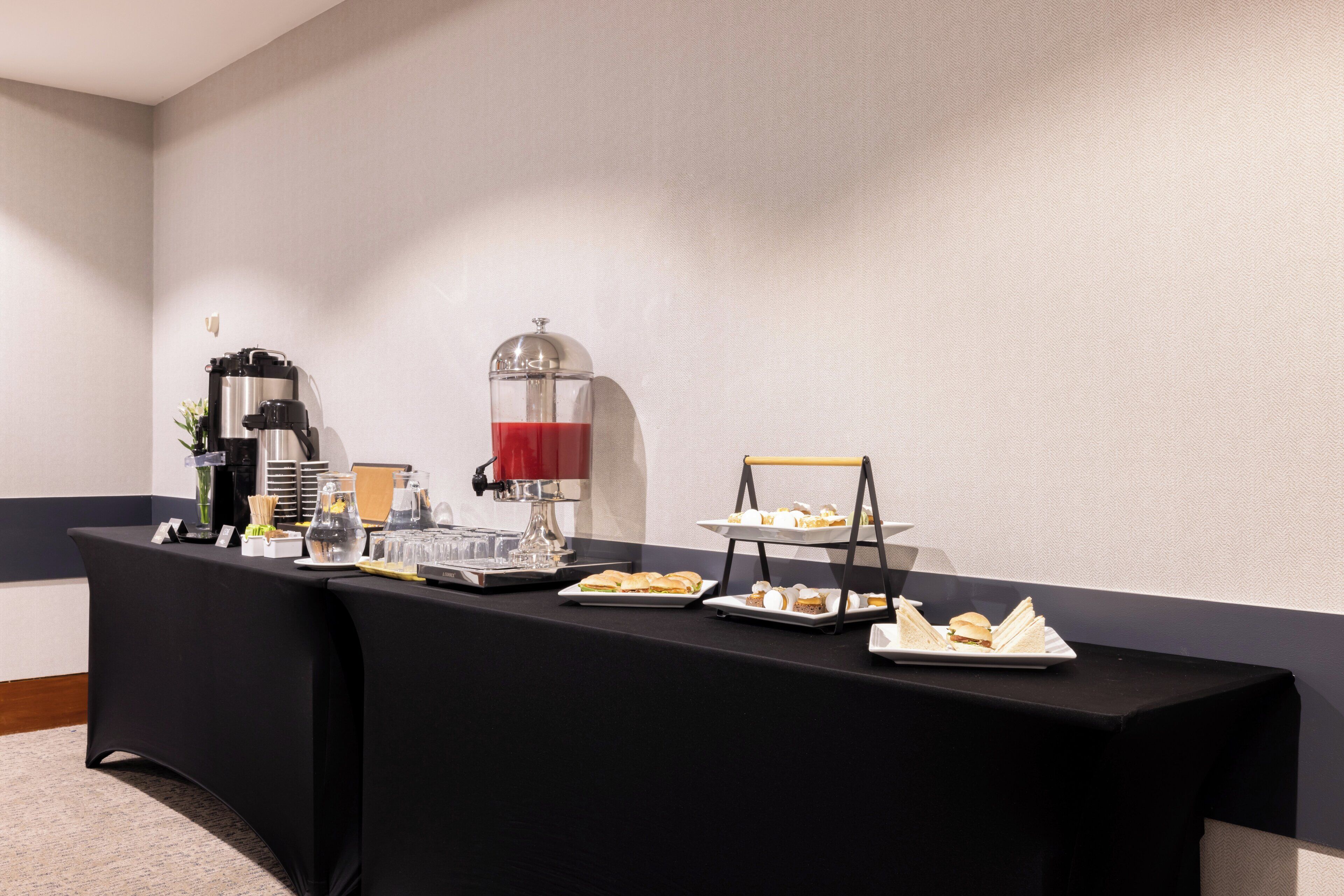 Uma mesa de buffet com diversos alimentos e uma máquina de café.