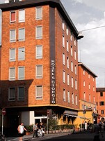 Um hotel com fachada de tijolos, várias janelas e uma placa com a inscrição 'HOTEL S. ORGIO'.