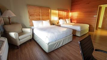 Quarto de hotel com duas camas, uma cadeira, um abajur e um aquecedor.