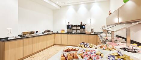 Uma área de buffet com diversos tipos de comida e um espaço para café.