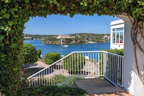 Vista costeira com um edifício branco, uma escadaria e um mar azul límpido.