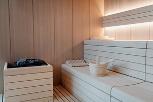 Uma sauna moderna com painéis de madeira, um banco e um balde.