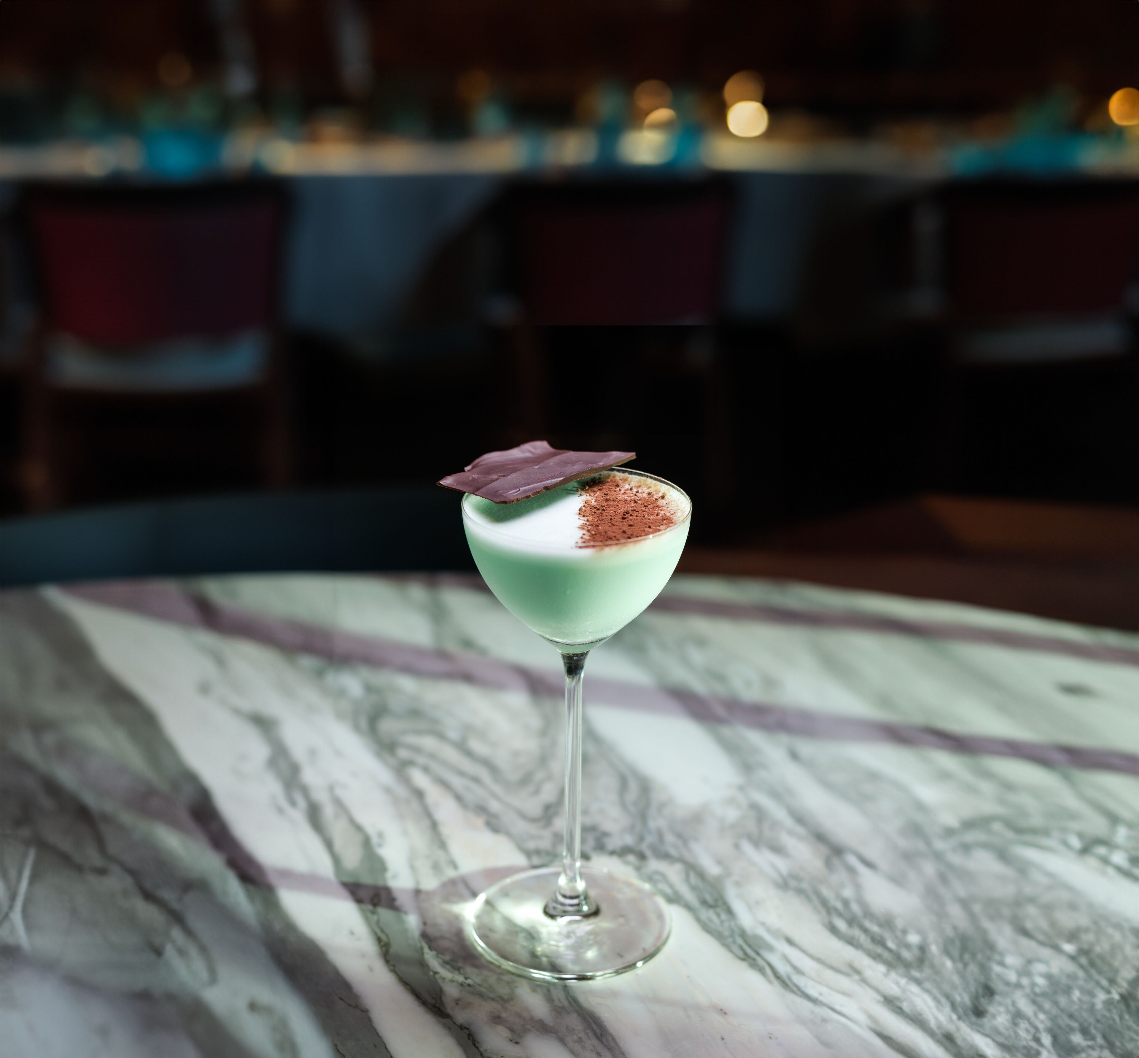 Um cocktail num copo sobre uma mesa de mármore.