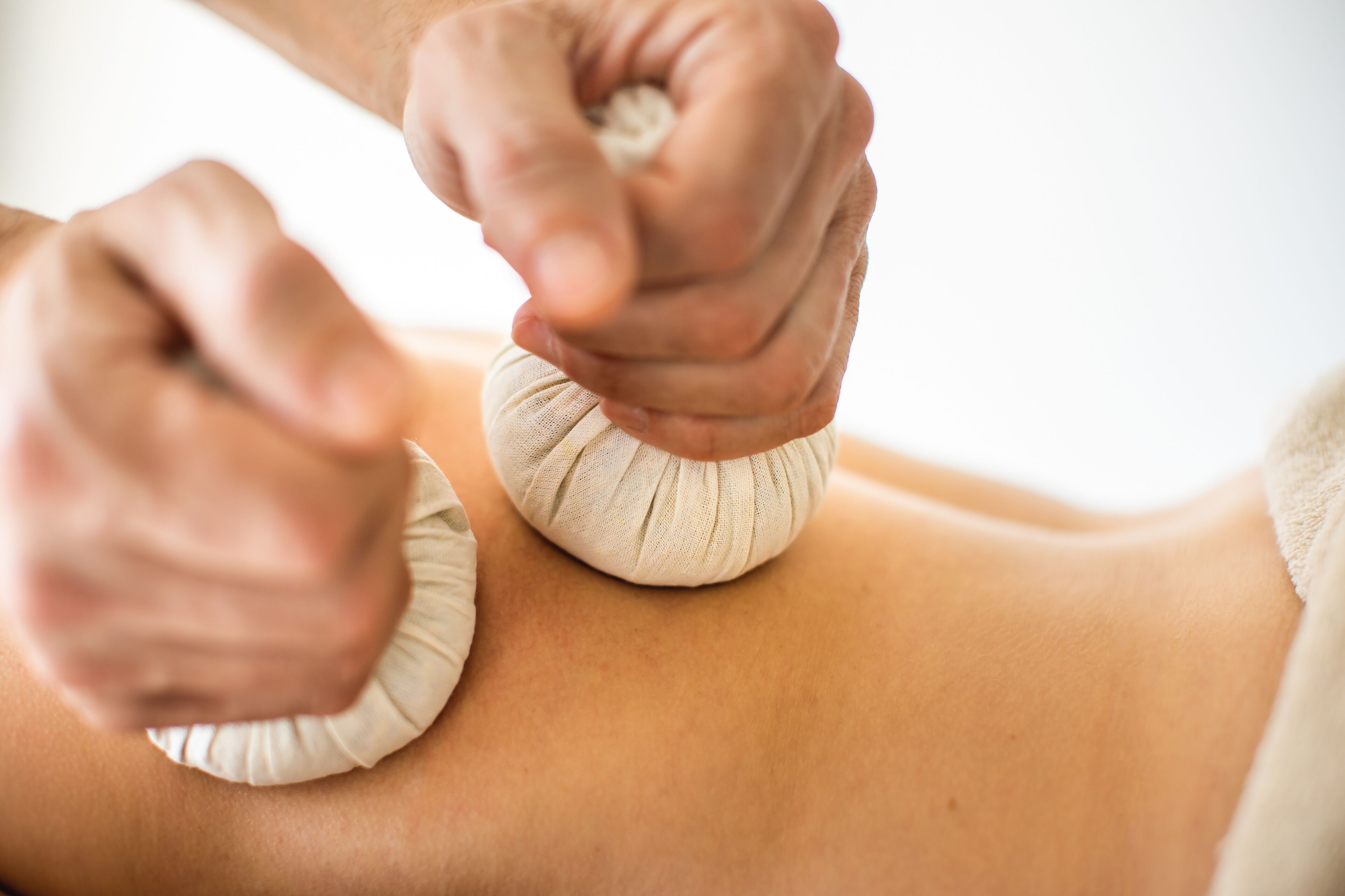 Primeiro plano de mãos massageando as costas de uma pessoa.