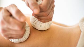 Primeiro plano de mãos massageando as costas de uma pessoa.