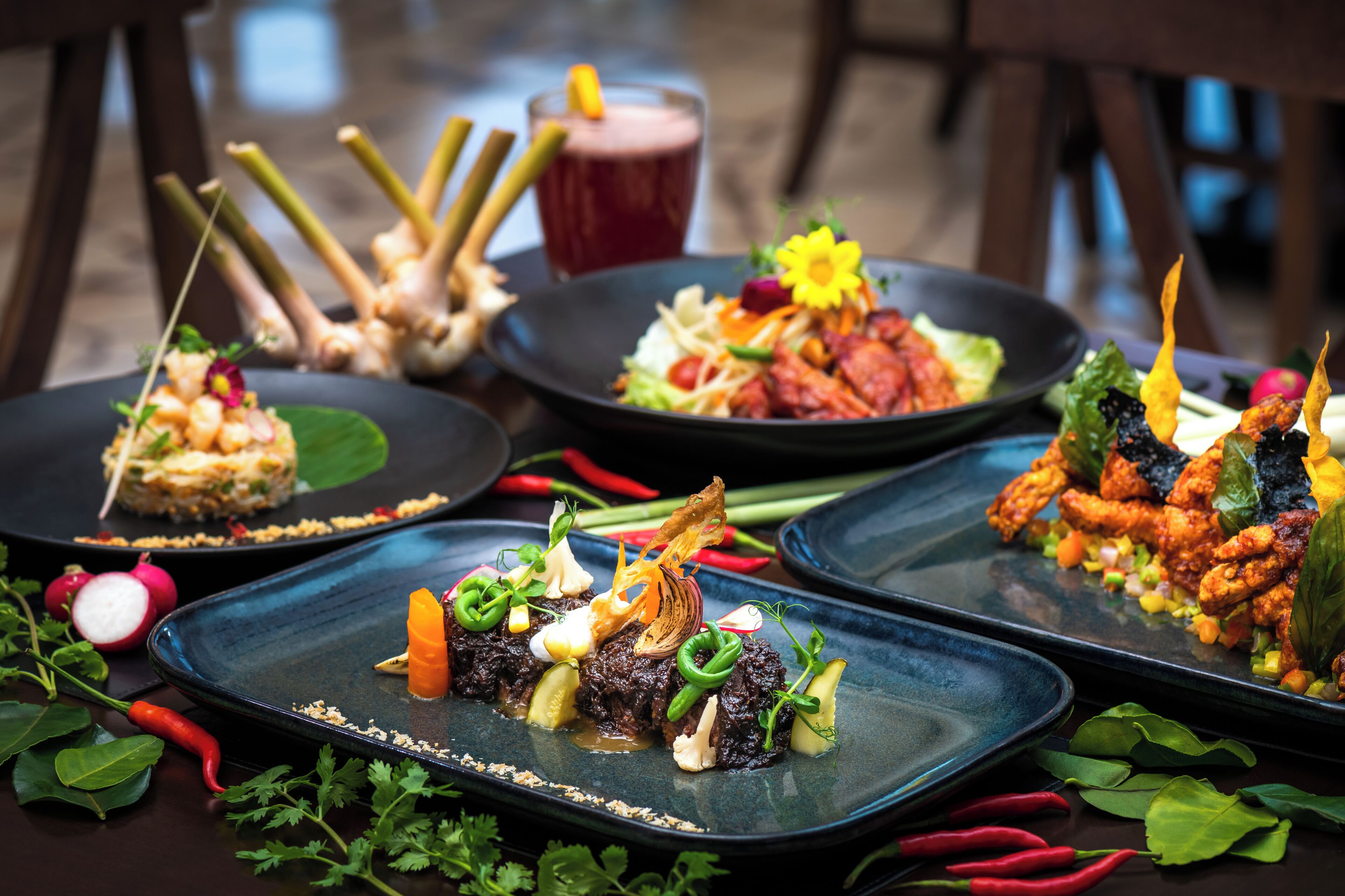Uma mesa com diversos pratos, incluindo uma salada, um prato de carne e uma sobremesa, decorada com ervas e vegetais.