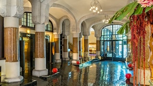 Um hall amplo com pé direito alto, colunas em arco e piso refletivo.