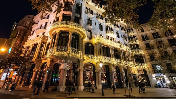 Um edifício histórico com varandas e colunas ornamentadas, apresentando uma entrada imponente e vários andares.
