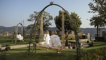 Um jardim com baloiços e uma fonte.