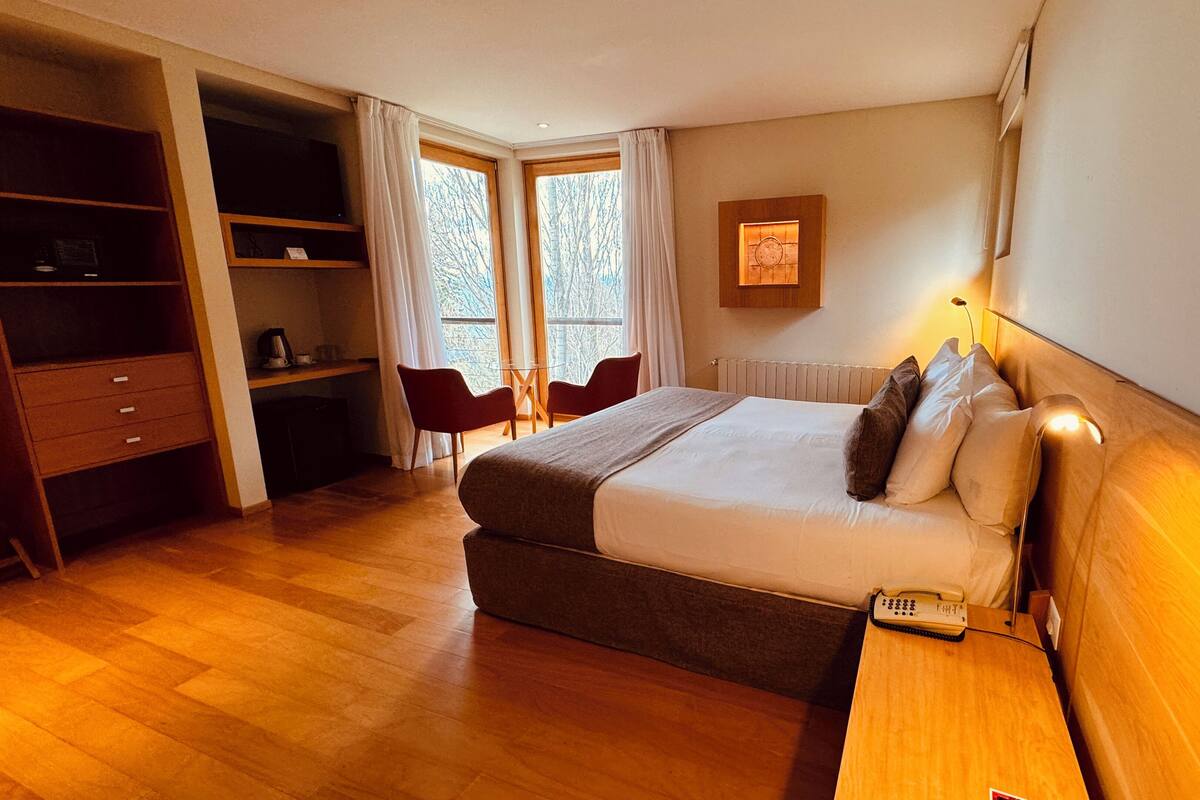 Quarto de hotel com uma cama grande, uma mesa, uma cadeira e um guarda-roupa.