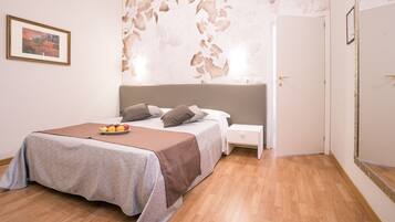 Quarto com cama, mesa de cabeceira e uma cesta de frutas na cama.