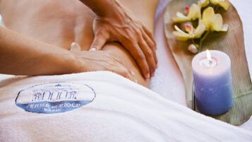 Close-up de uma sessão de massagem com uma toalha e uma vela sobre a cama.