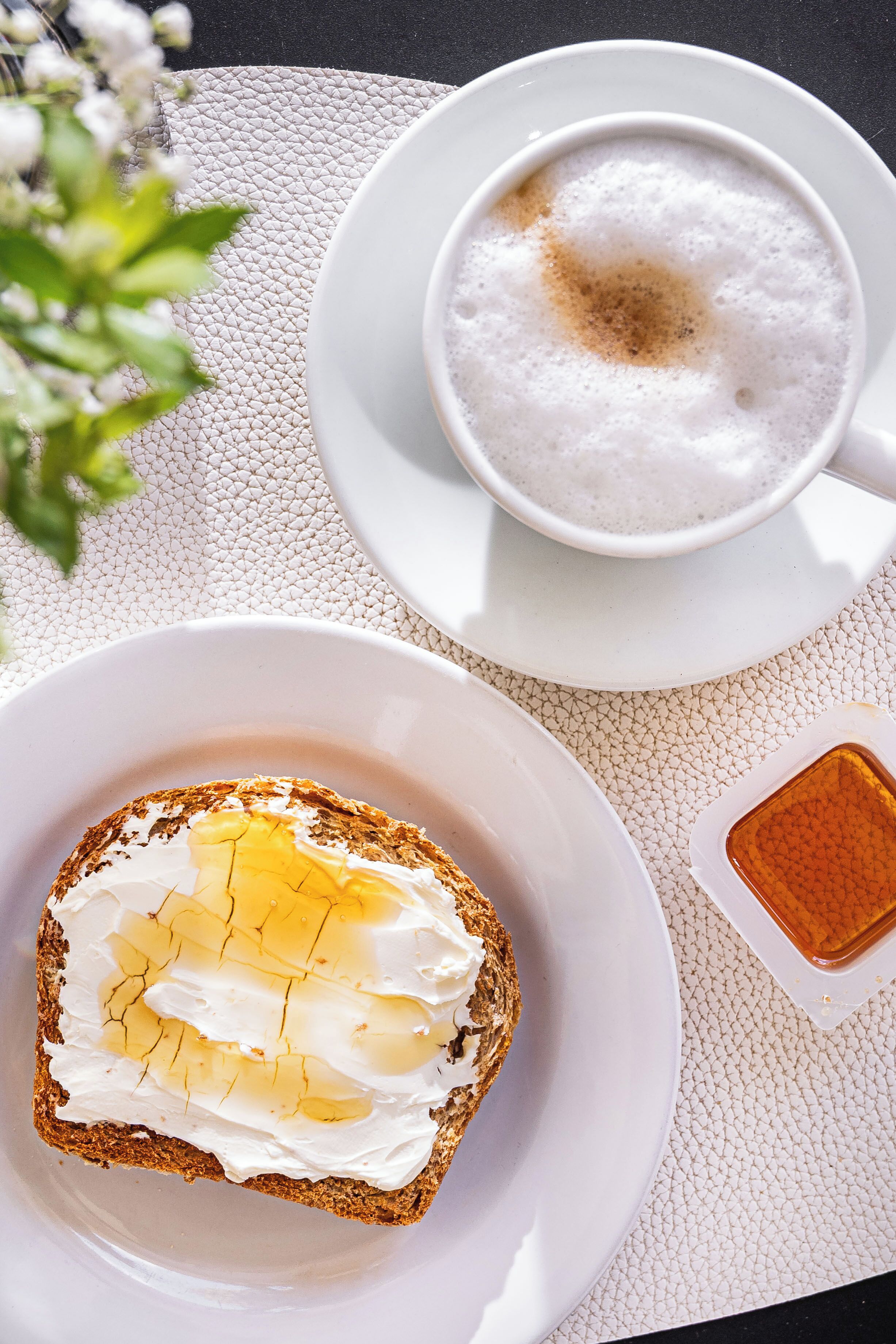 Uma mesa de café da manhã com torradas, uma xícara de café e um pires de mel.