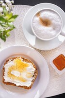 Uma mesa de café da manhã com torradas, uma xícara de café e um pires de mel.