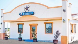 Um hotel Travelodge com um logotipo em forma de estrela, uma placa de boas-vindas e plantas em vasos na entrada.