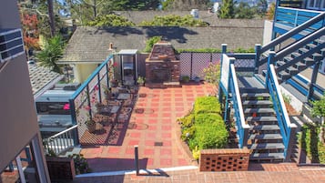 Um terraço no telhado com área de estar ao ar livre, churrasqueira e vista do bairro.