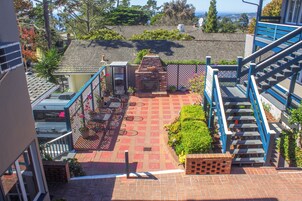 Um terraço no telhado com área de estar ao ar livre, churrasqueira e vista do bairro.