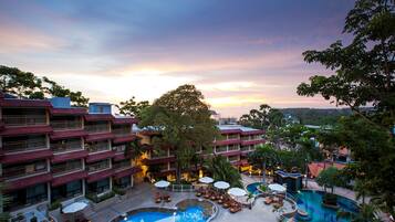 Um hotel com várias varandas, piscina e áreas de estar ao ar livre.