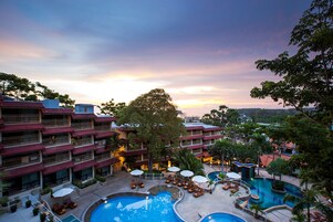 Um hotel com várias varandas, piscina e áreas de estar ao ar livre.