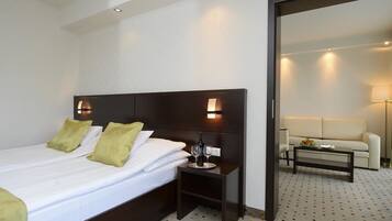 Quarto de hotel com uma cama grande, luminárias de cabeceira, uma mesinha com bandeja, um sofá e uma mesa de centro.
