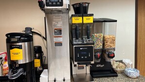 Estação de café com máquina de espresso Bunn, cafeteira Keurig e dispensador de água.