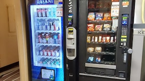 Duas máquinas de venda automática de bebidas em um corredor com carpete estampado.
