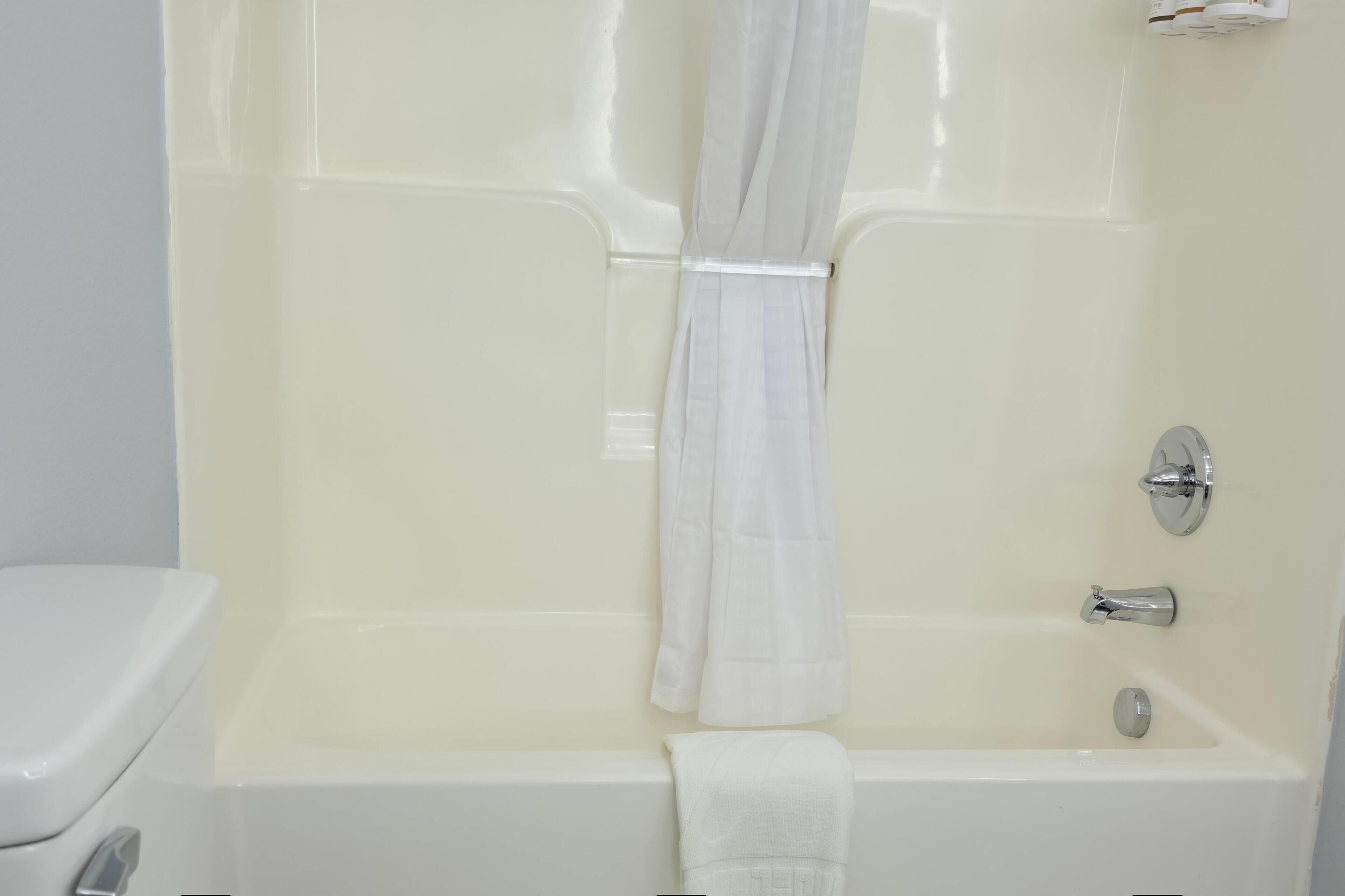 Um banheiro com banheira, vaso sanitário e cortina de chuveiro.