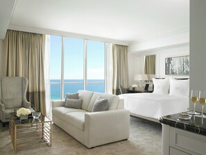 Quarto de hotel com uma janela grande, um sofá, uma cama, uma escrivaninha e um minibar.