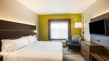 Quarto de hotel com uma cama grande, televisão de tela plana, escrivaninha e uma cadeira.