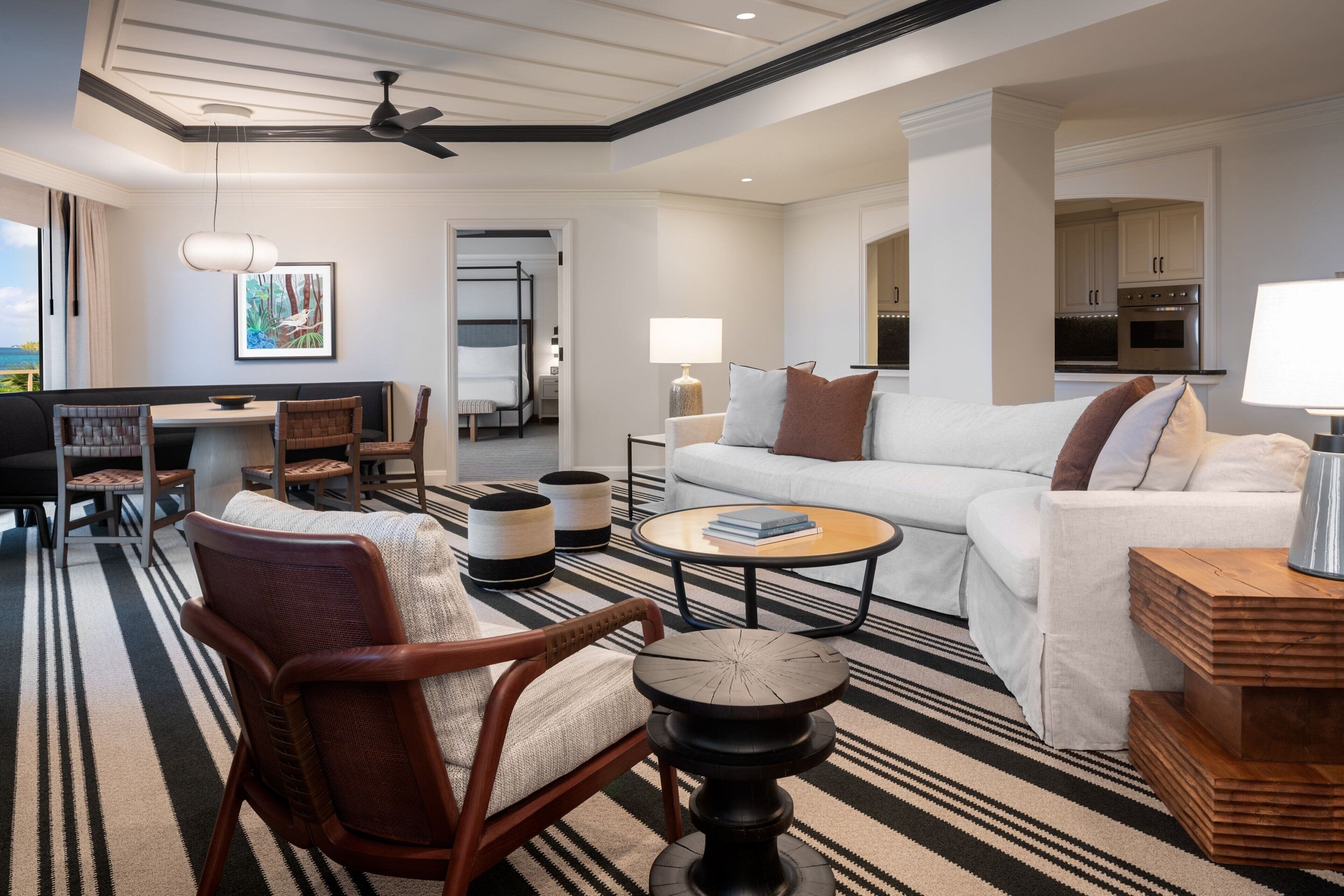 Uma sala de estar moderna com um sofá, poltronas, uma mesa de centro e um espaço de refeições com cadeiras e mesa.