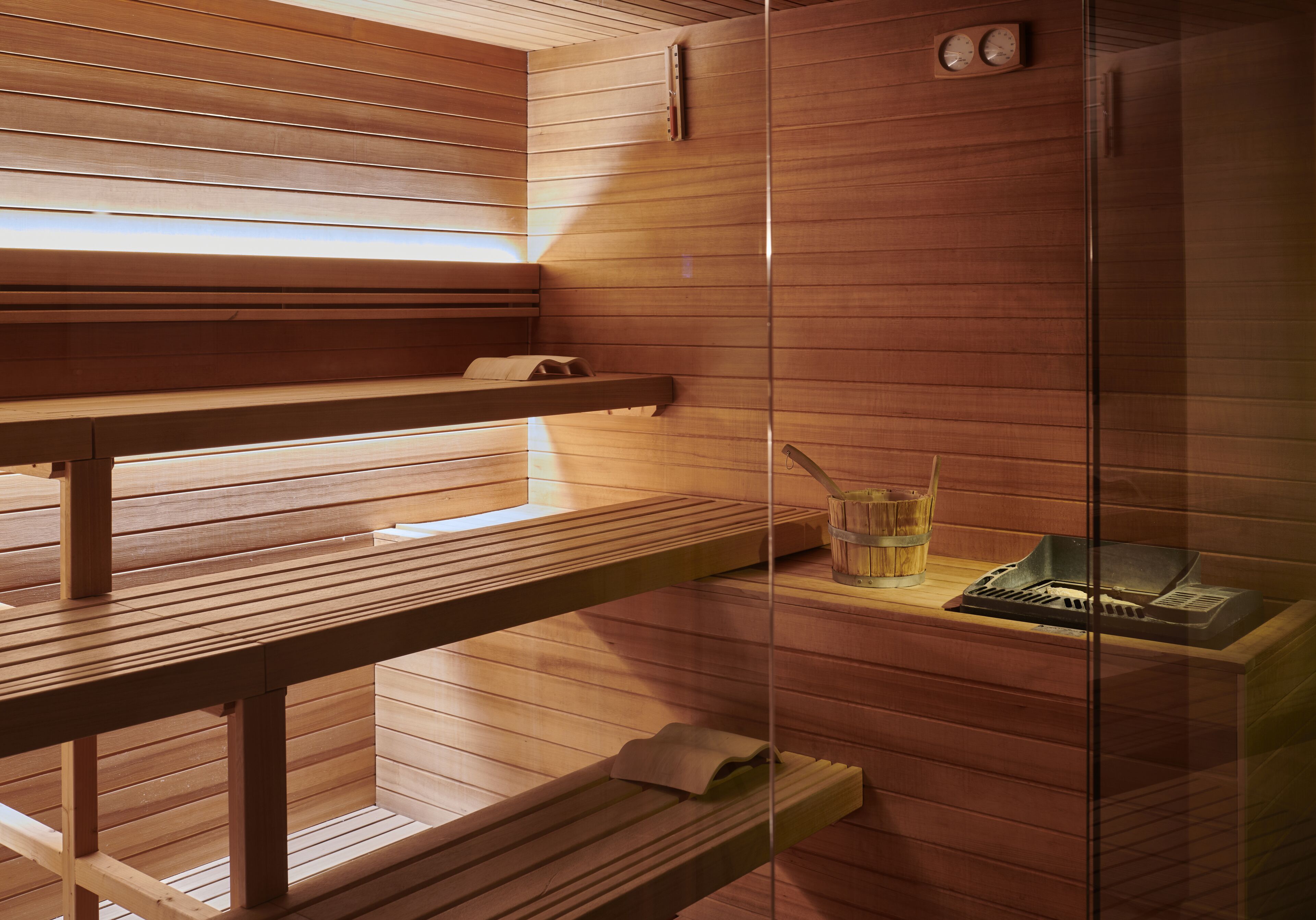 Uma sauna com bancos de madeira e divisória de vidro.