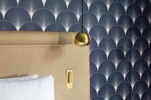 Um quarto com papel de parede estampado, parede dourada e travesseiro branco.